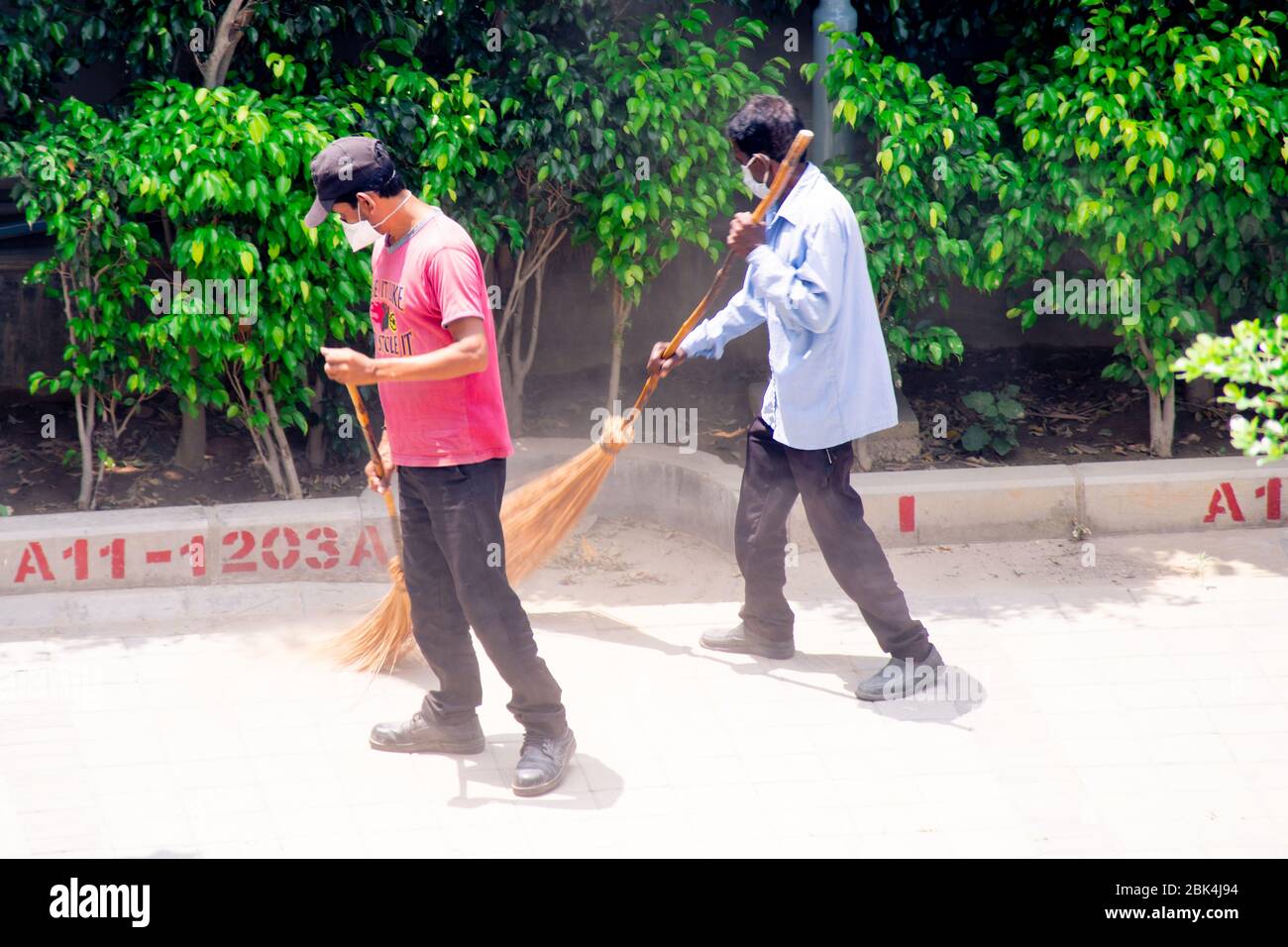 Male sweeper in blue uniform cleaning street and sidewalks with long ...