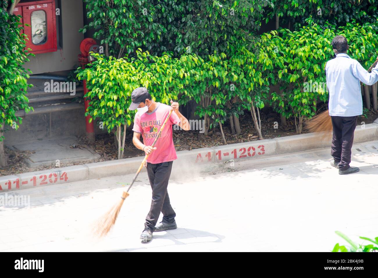 Male sweeper in blue uniform cleaning street and sidewalks with long ...