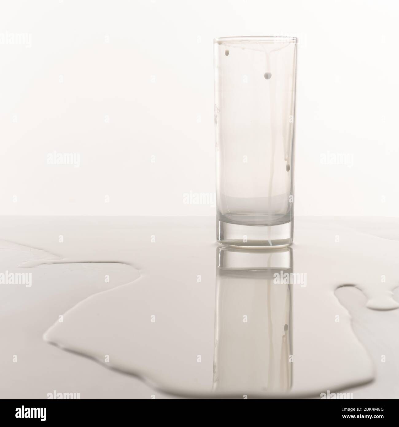 White milk spilled and splash on the white floor surface and empty ...