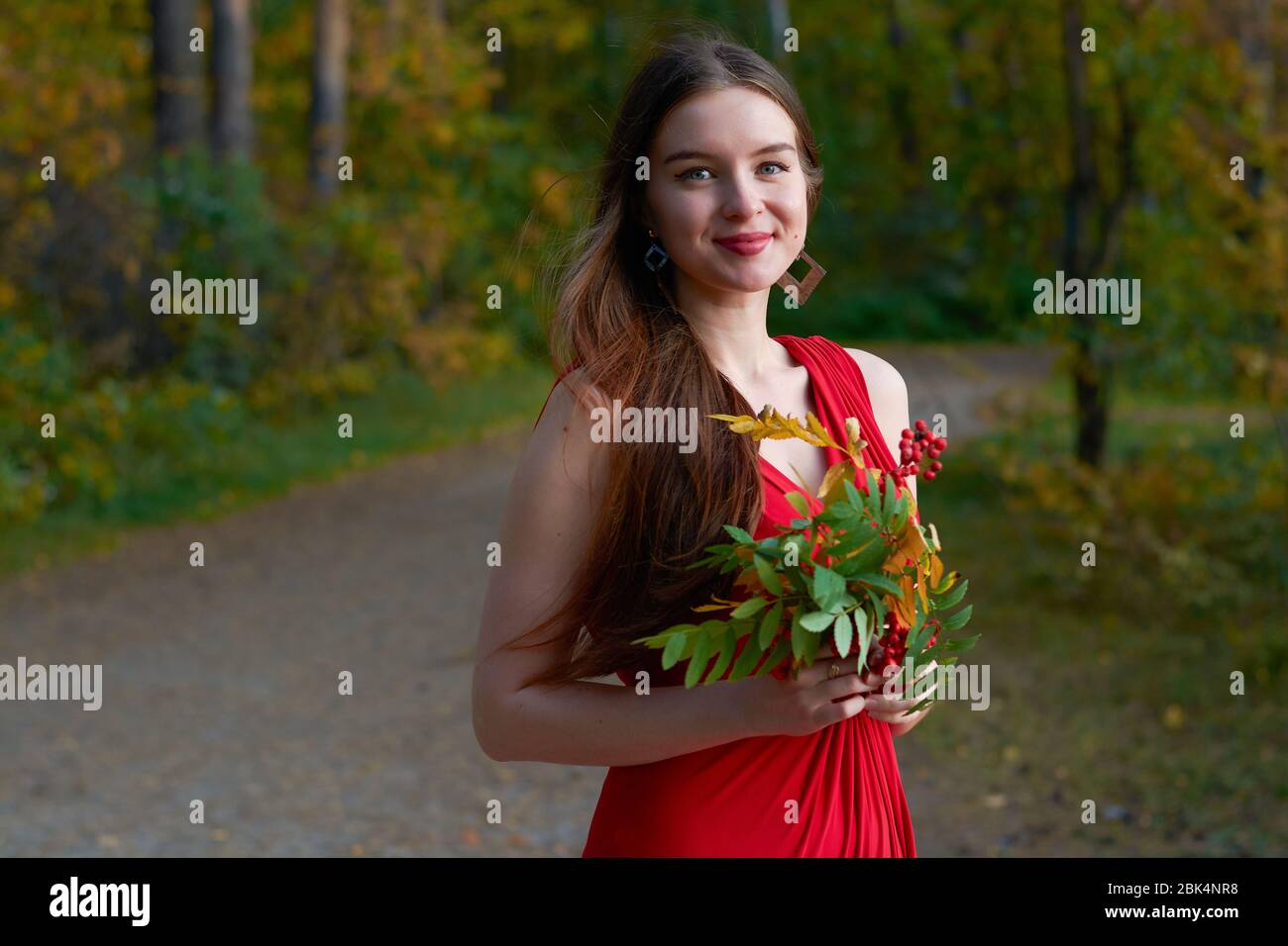 Girl in red dress with a bouquet of ash trees in the woods Stock Photo ...