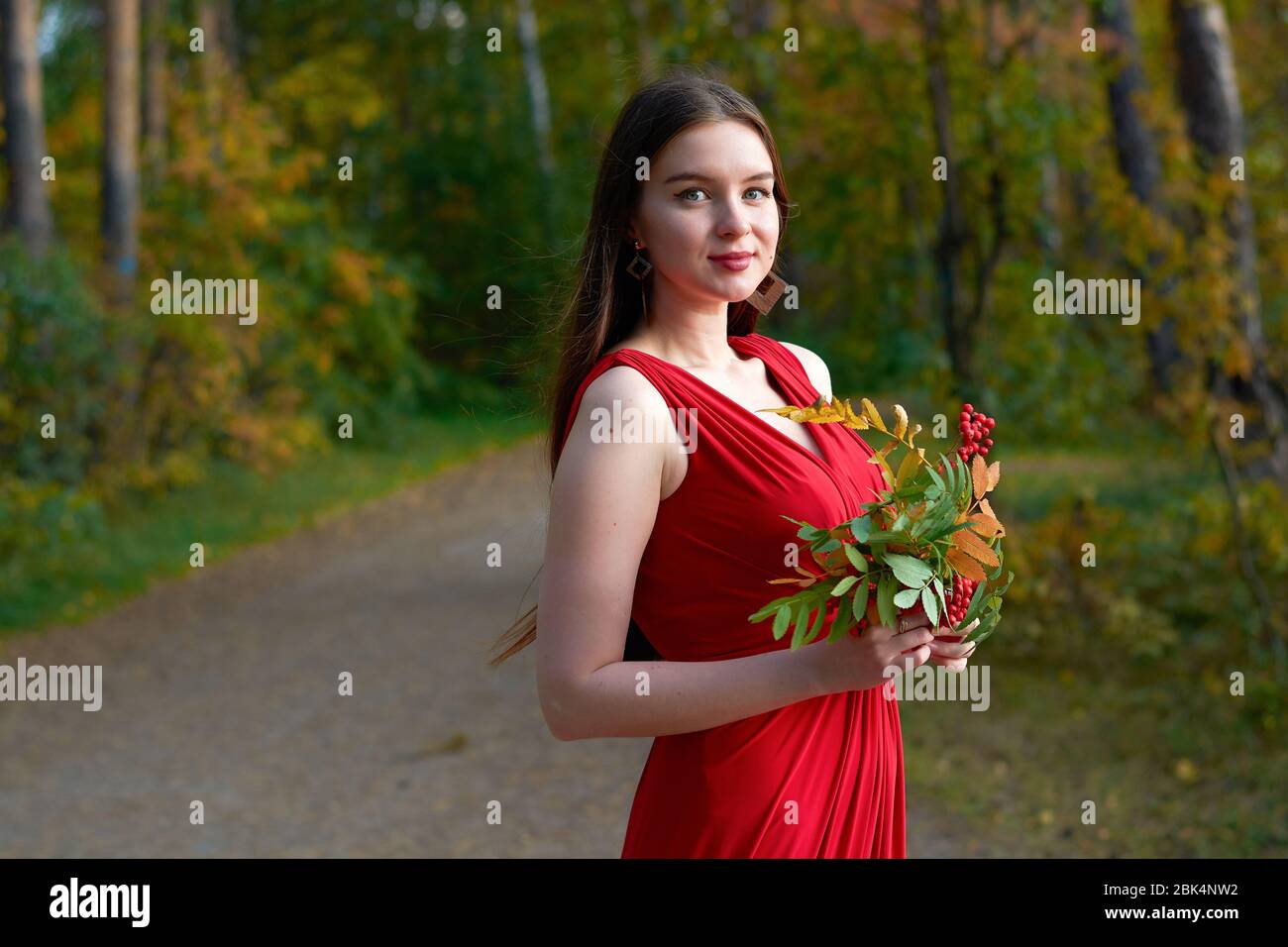 Girl in red dress with a bouquet of ash trees in the woods Stock Photo ...