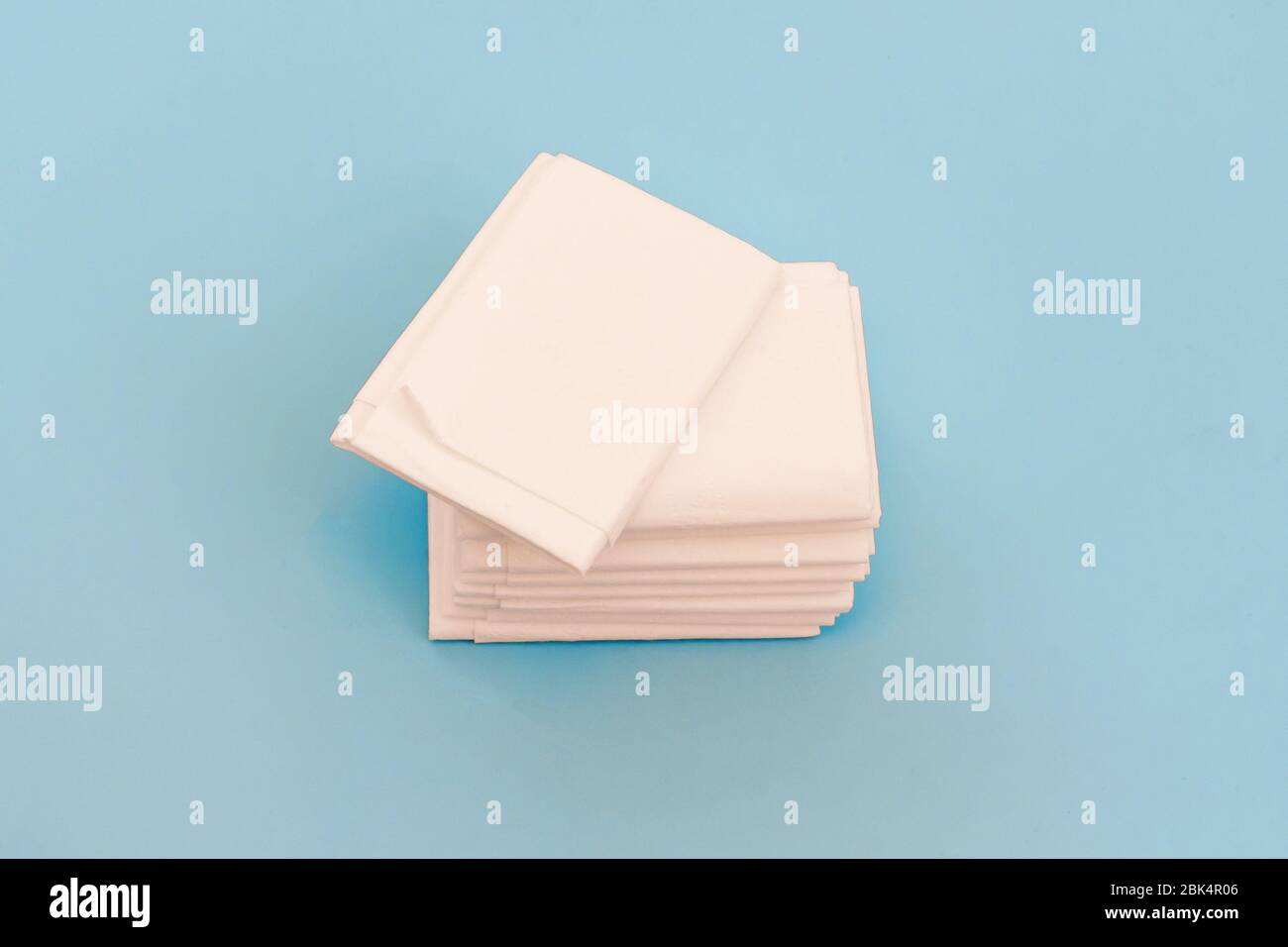 A pack of new hygienic white paper tissues or napkins on light blue ...