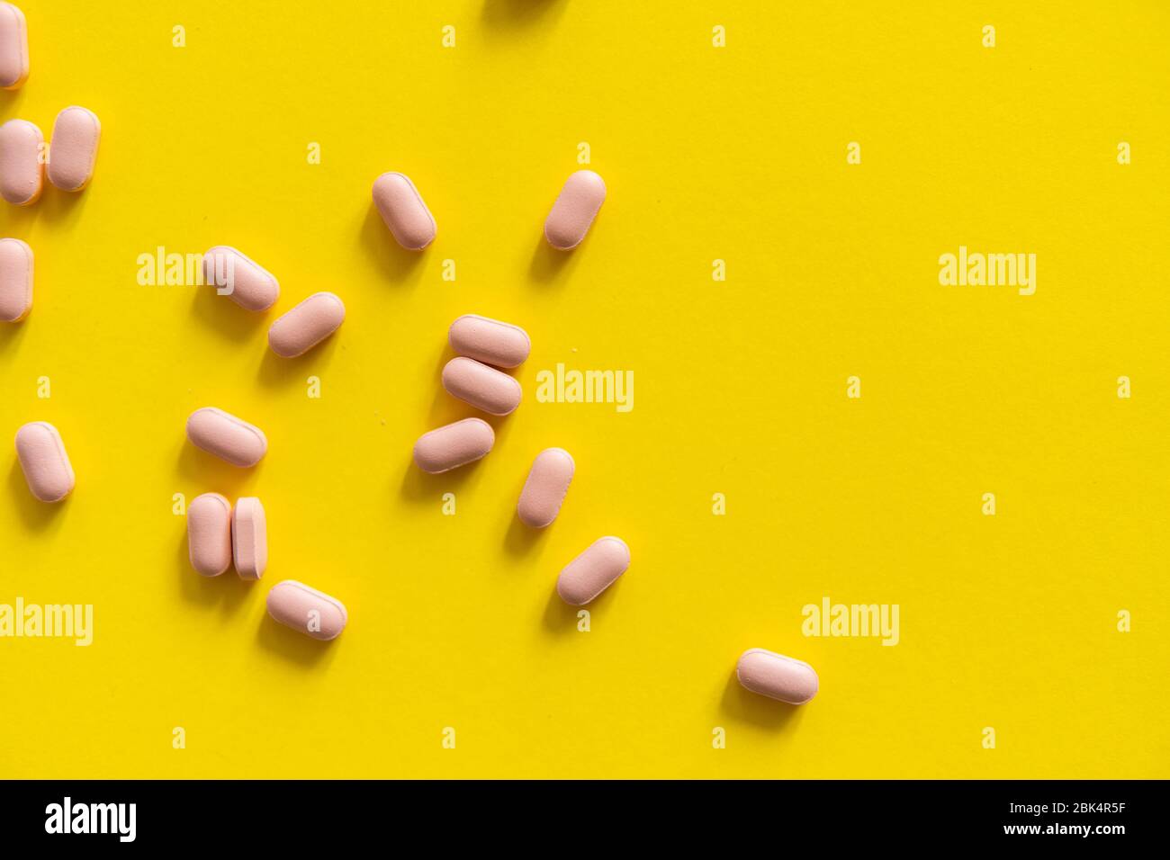 Pink pills on yellow background. Medicine, medication, painkillers ...