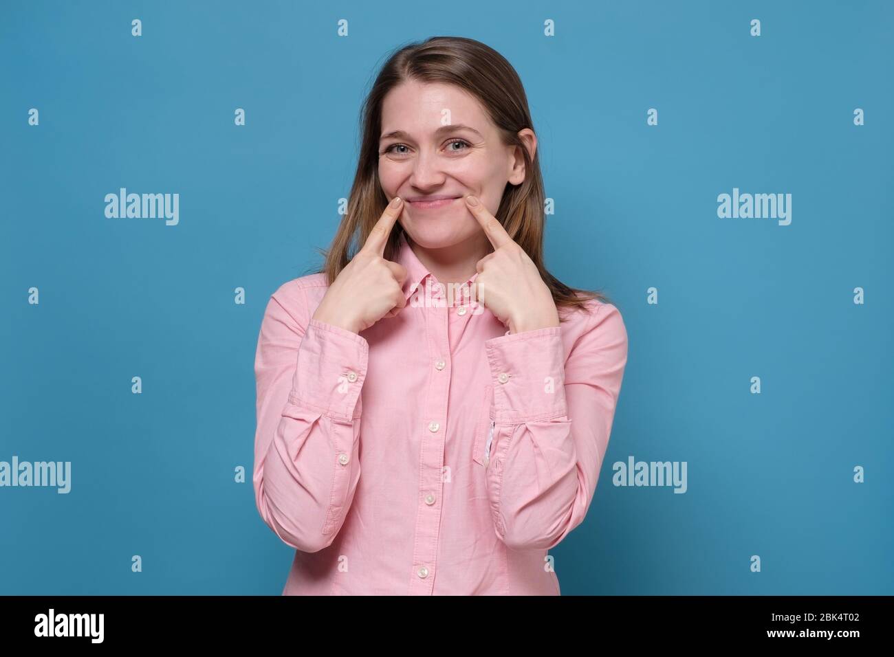 Caucasian young woman tries to pretend she is happy in front of people ...