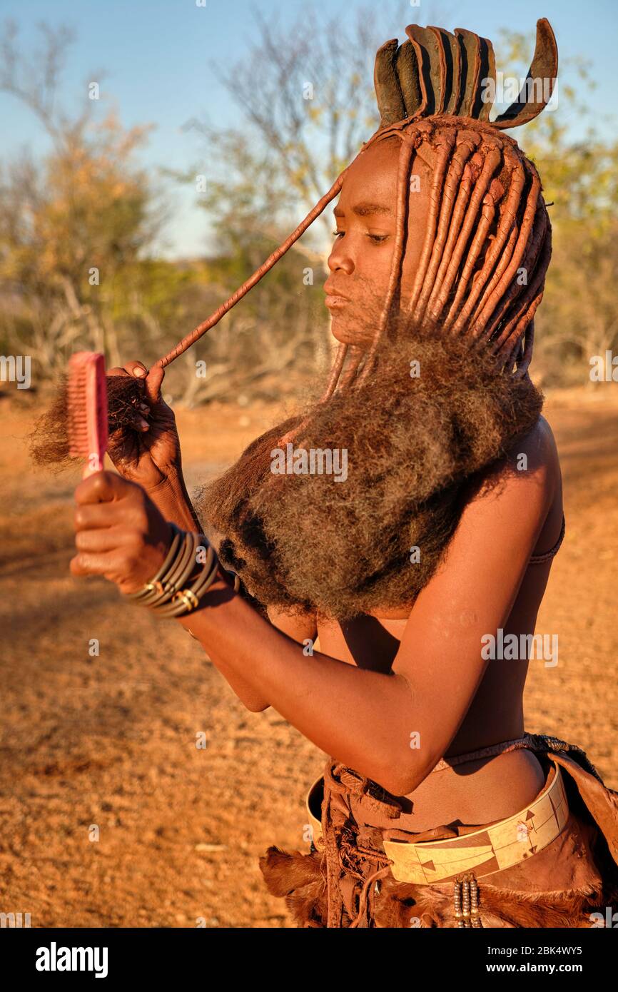 Batwa girl in traditional dress combing her hair at sunset Stock Photo ...