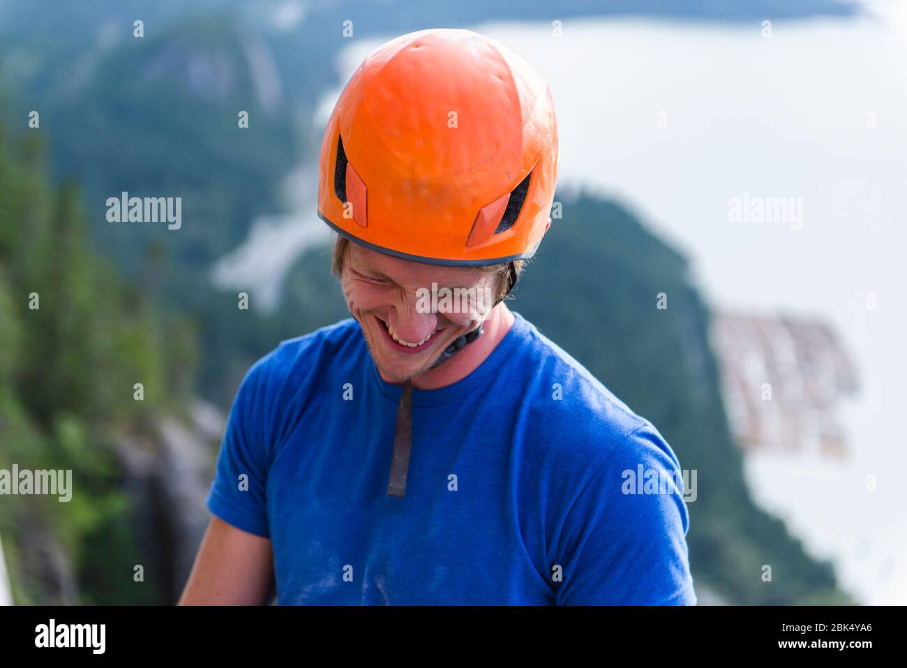 Climber with helmet smiling and laughing looking down above water Stock ...