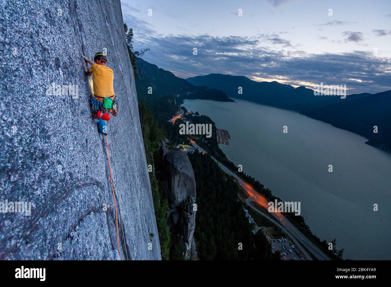 Side view man rock climbing at sunset above the sea and highway Stock ...