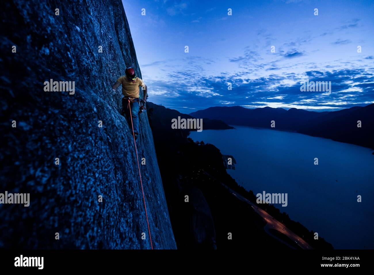 Side view man rock climbing at night above the sea and highway Stock ...