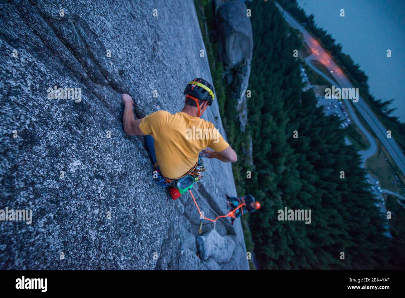Top view man rock climbing at sunset above the sea and highway Stock ...
