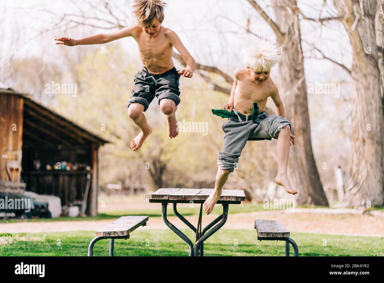 Two boys jumping off picnic table Stock Photo - Alamy