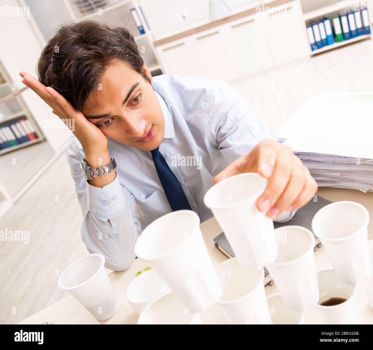 The young employee building pyramid from plastic cups Stock Photo - Alamy