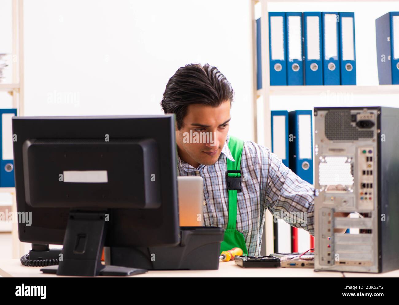 The young engineer repairing broken computer at the office Stock Photo ...