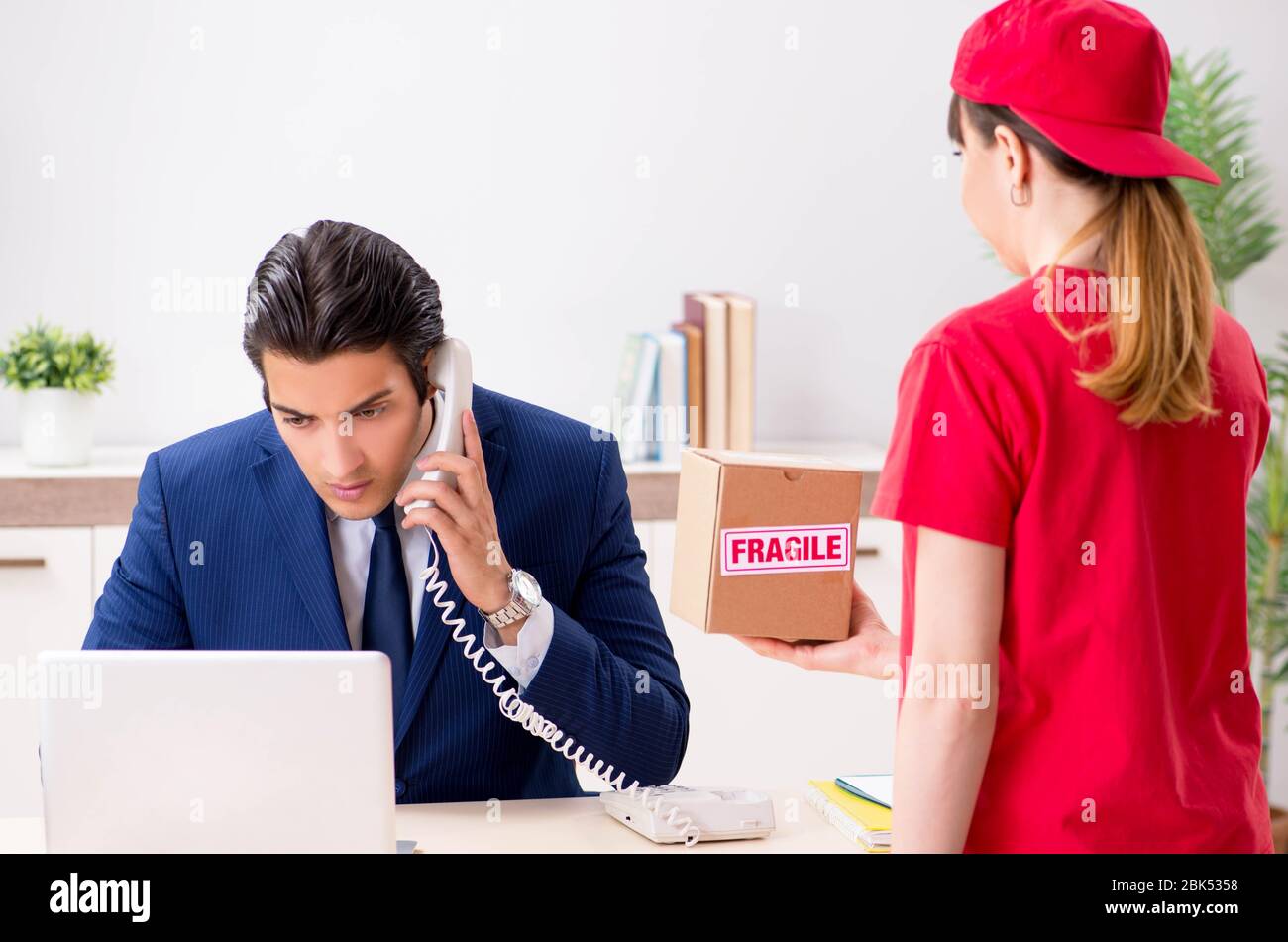 The courier delivering parcel to the office Stock Photo - Alamy