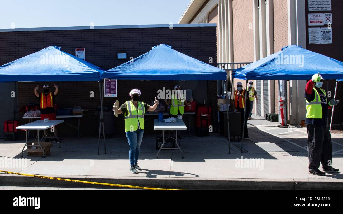 Volunteers give thumbs up sign while helping to give out food at food ...