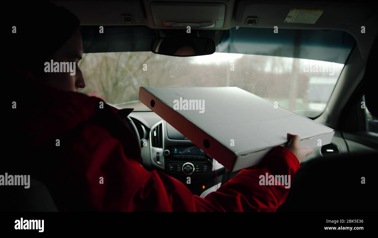 A delivery man drives a car and holding a pizza box. Mid shot Stock ...