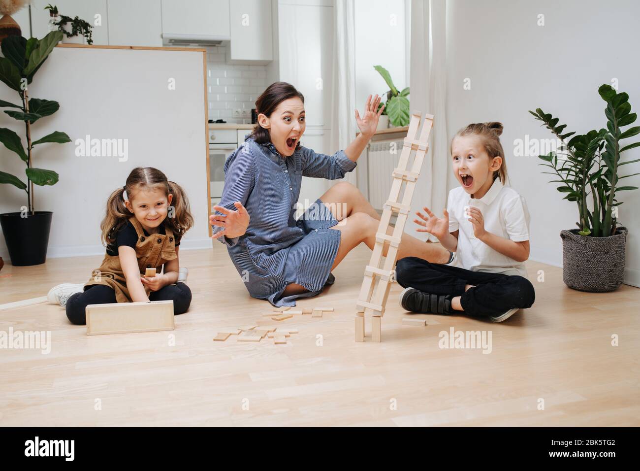 Mom and children watching toy tower collapse emotionally Stock Photo ...