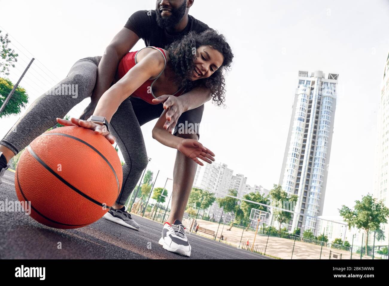 Outdoors Activity. African couple on basketball court girl dribbling ...