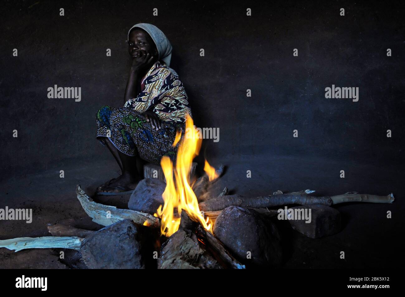 A villager sits by a bonfire in a rural settlement in Malawi Africa ...