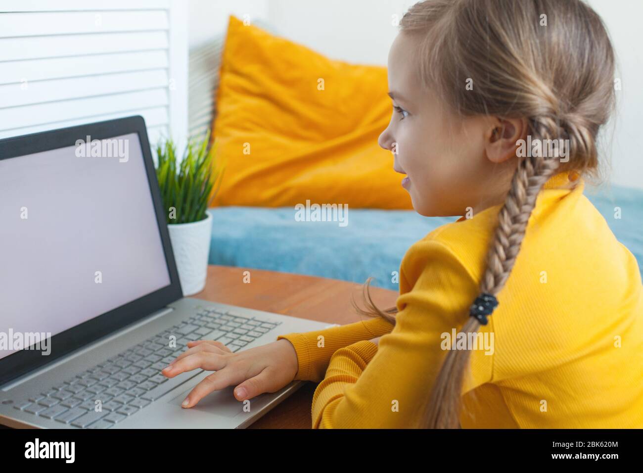 Cute child girl learning at home. Little girl using laptop with empty ...