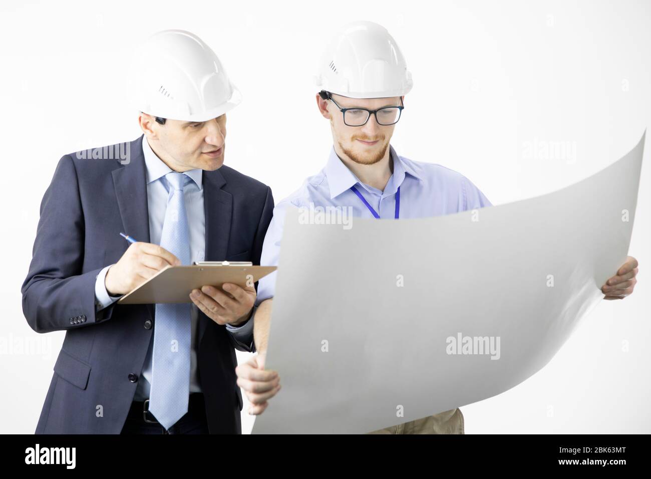 Architectural engineers working with blueprint documents marking edits ...