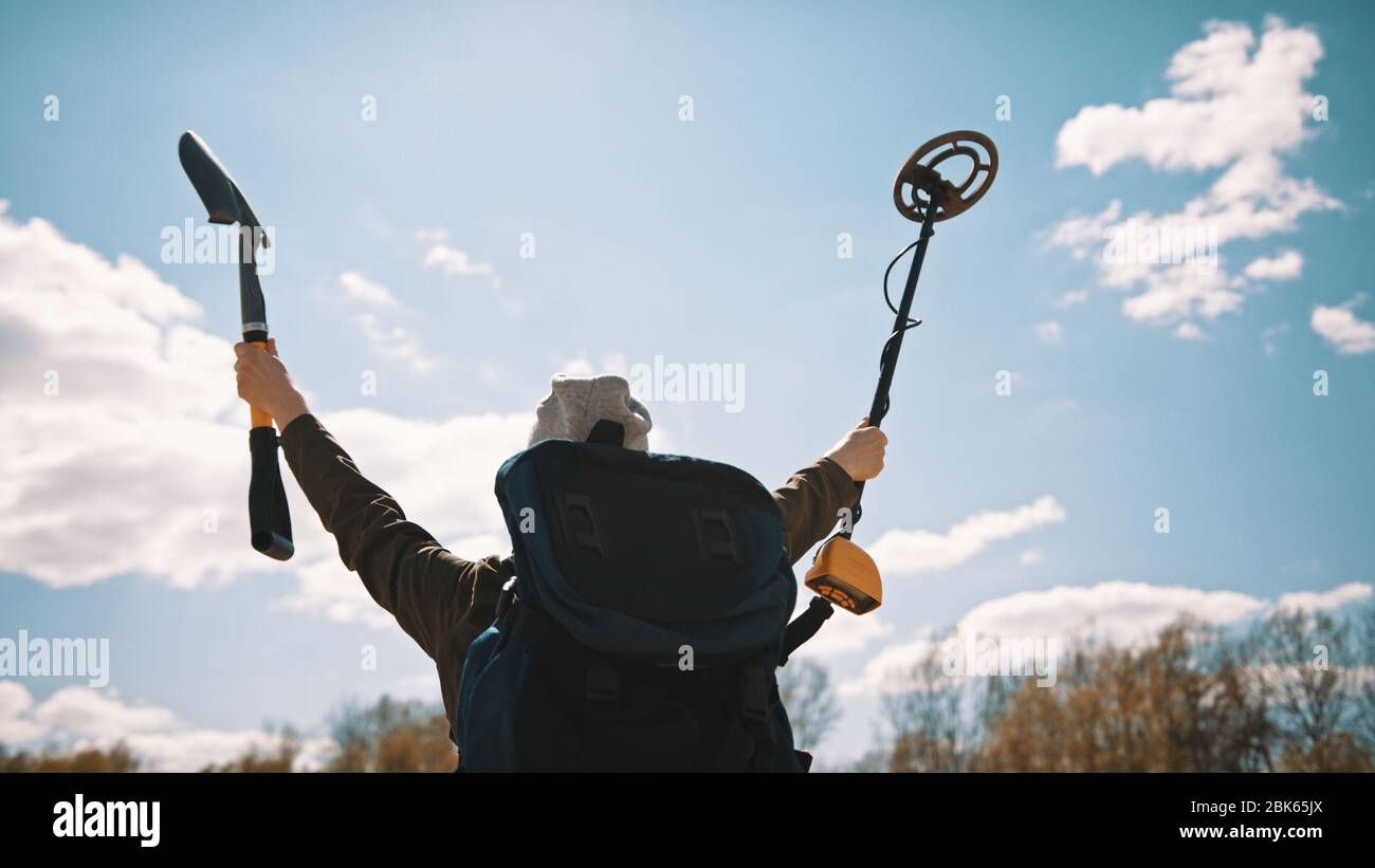 woman explorer crossing shovel and a metal detector in the air ...
