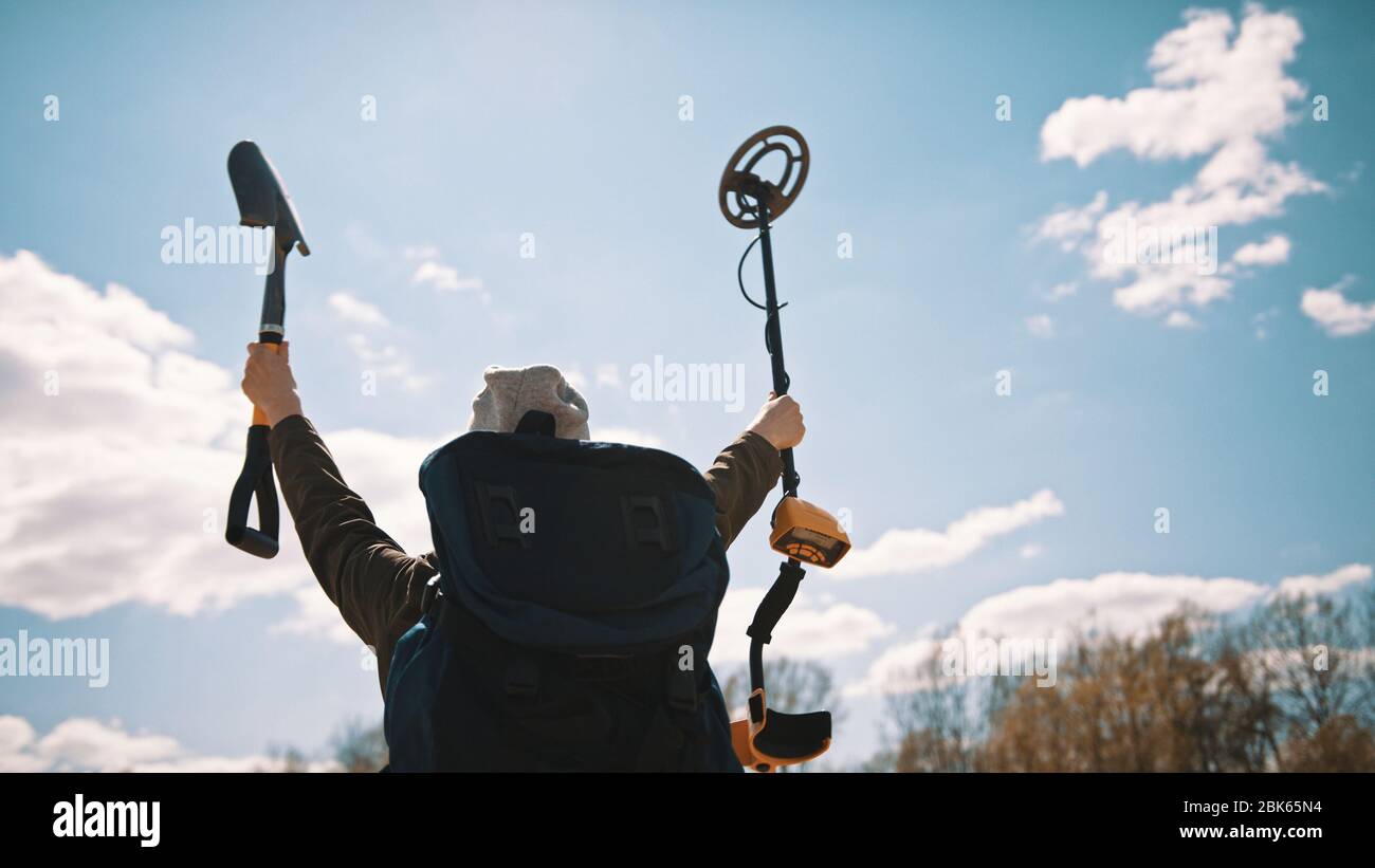 woman explorer crossing shovel and a metal detector in the air ...