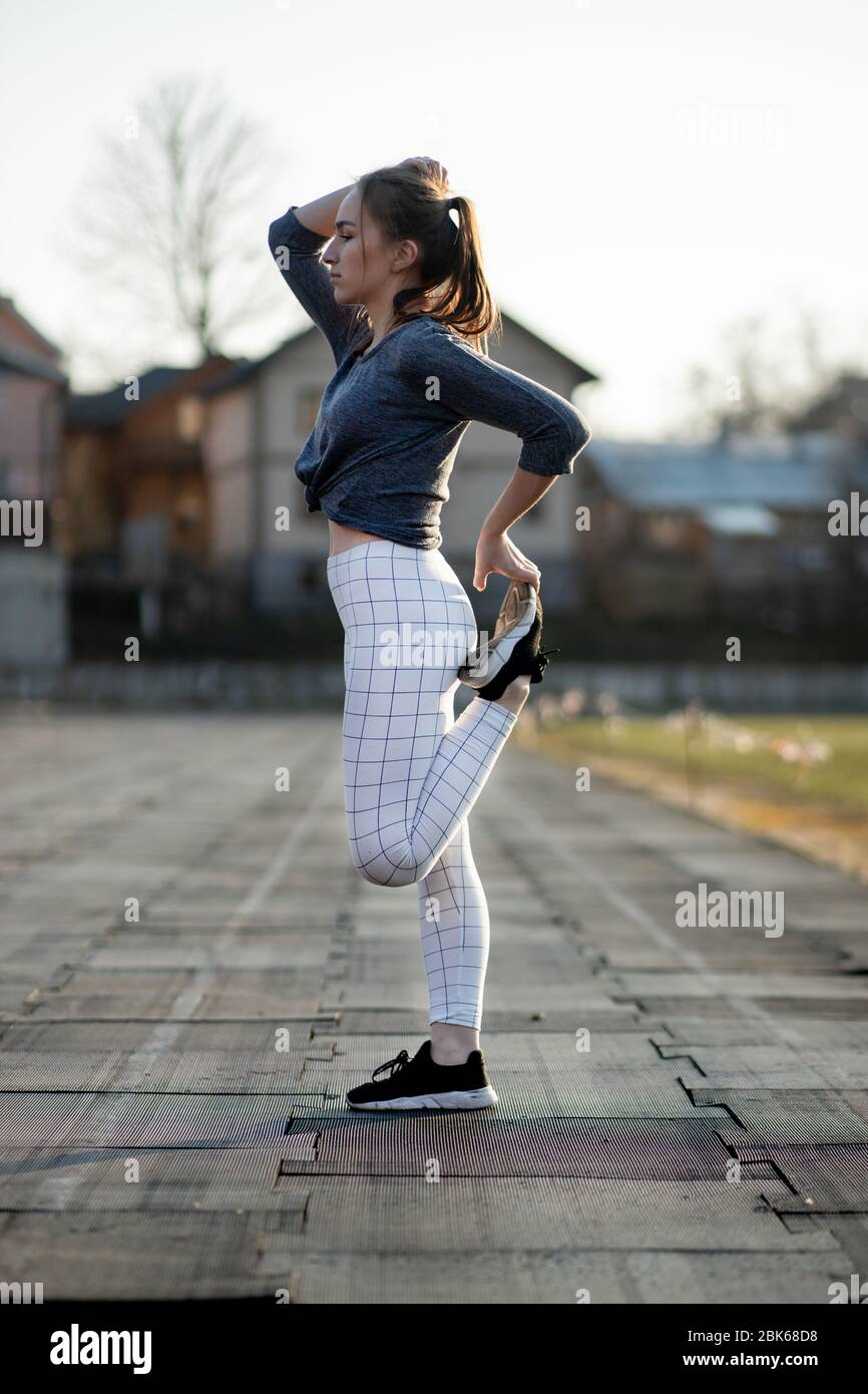 Female runner stretching legs on running track Stock Photo - Alamy