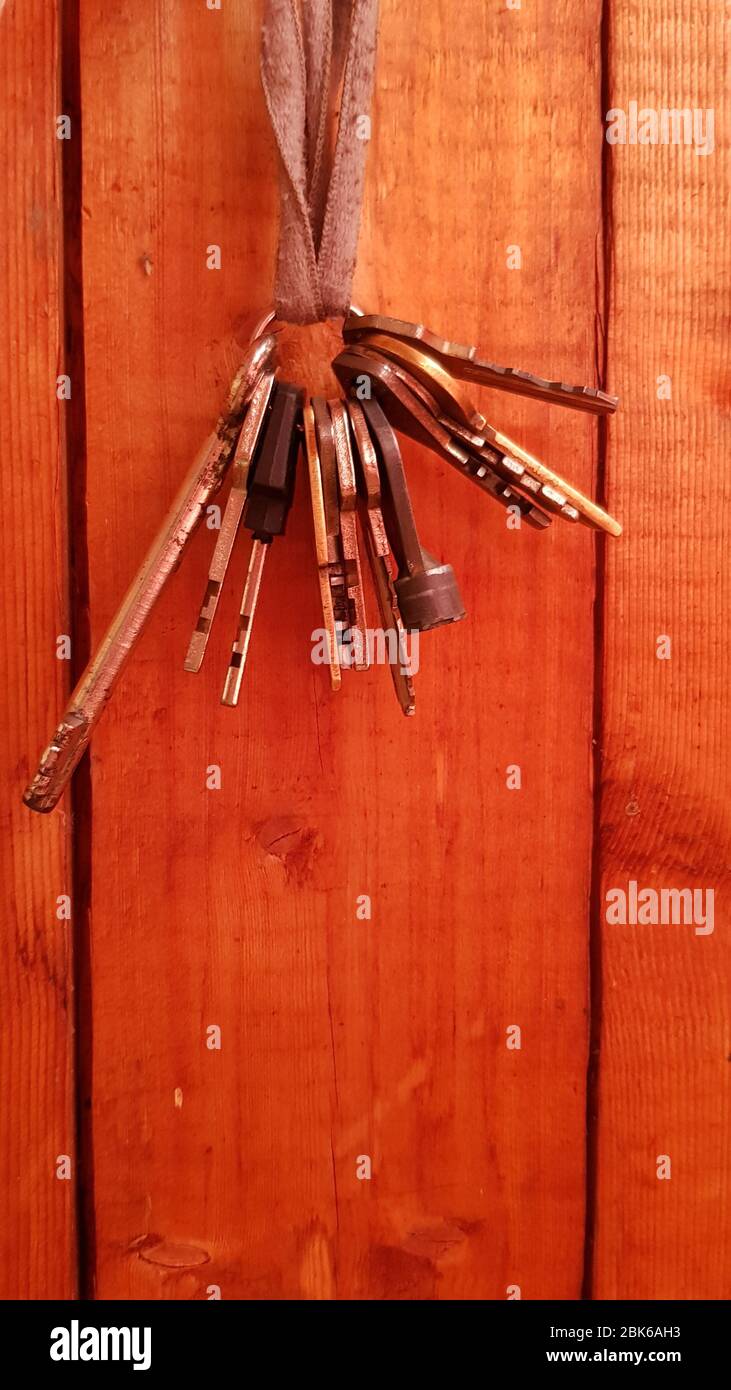 Old various keys hanging on dirty ribbon at rustic wood backdrop with ...