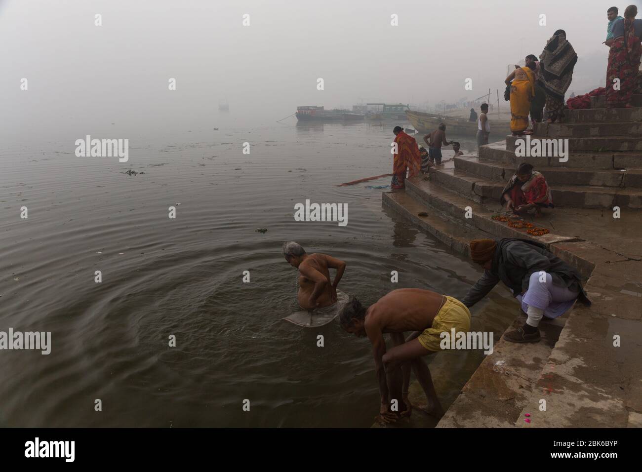 People taking bath on a foggy morning in the river Ganges near Varanasi ...