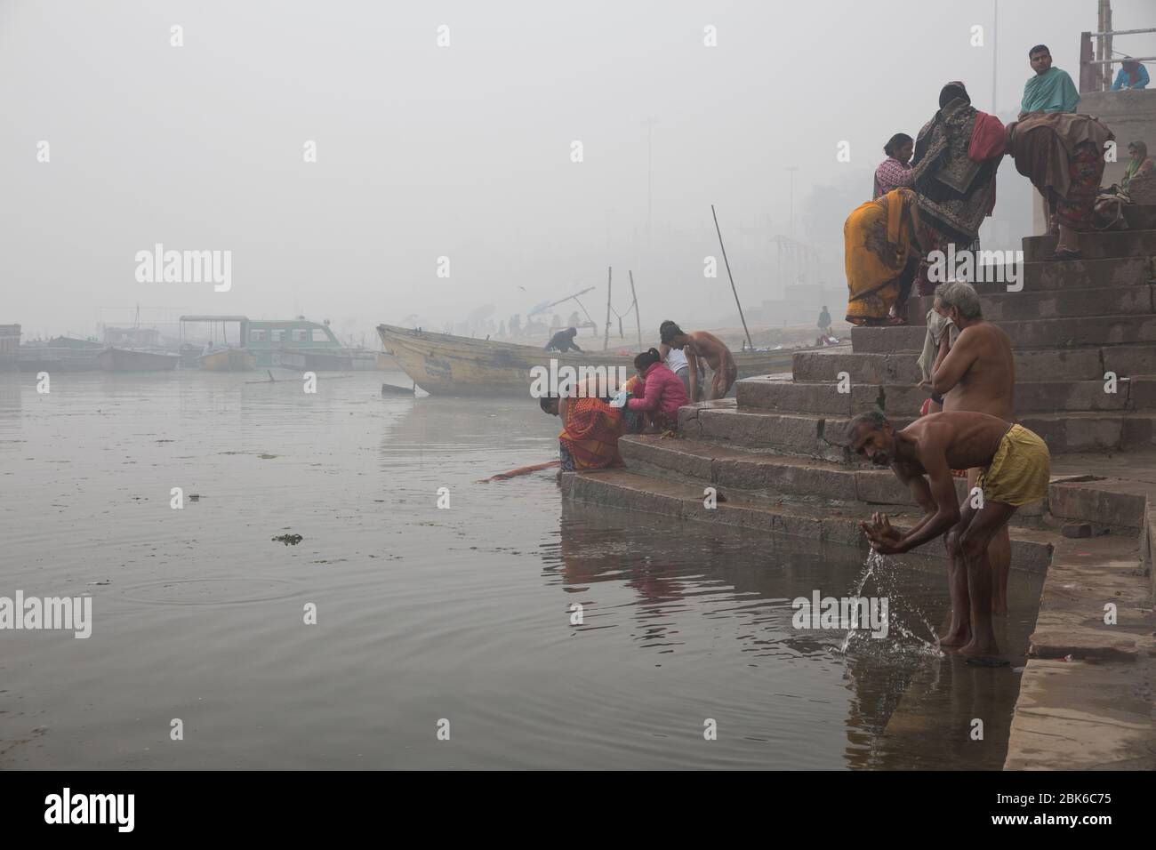 People taking bath on a foggy morning in the river Ganges near Varanasi ...