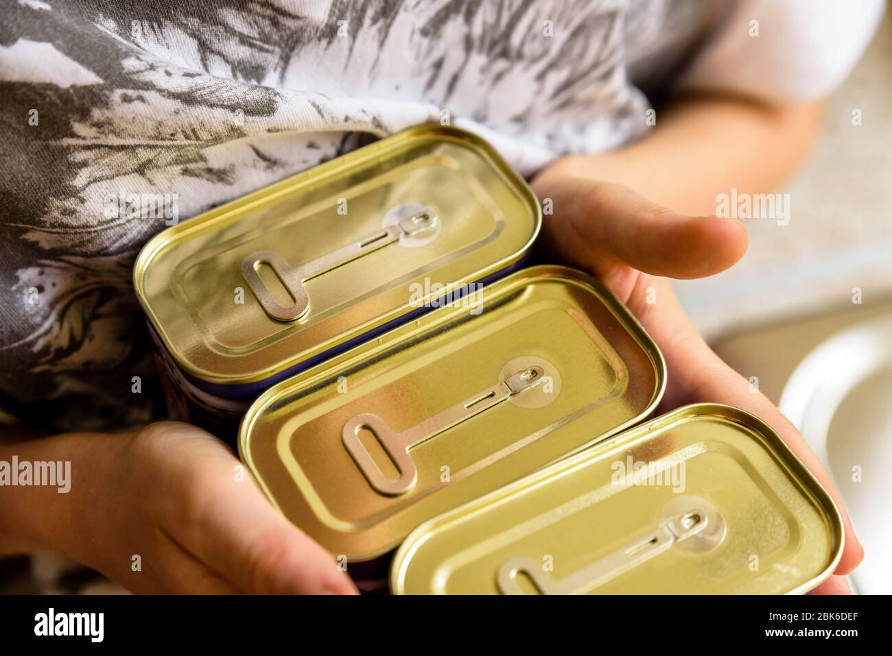 childs hands holding several canned food cans Stock Photo - Alamy