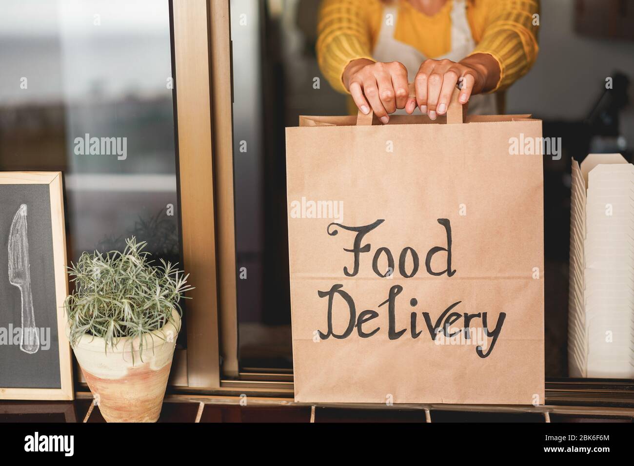 Young woman preparing food delivery inside ghost kitchen during ...
