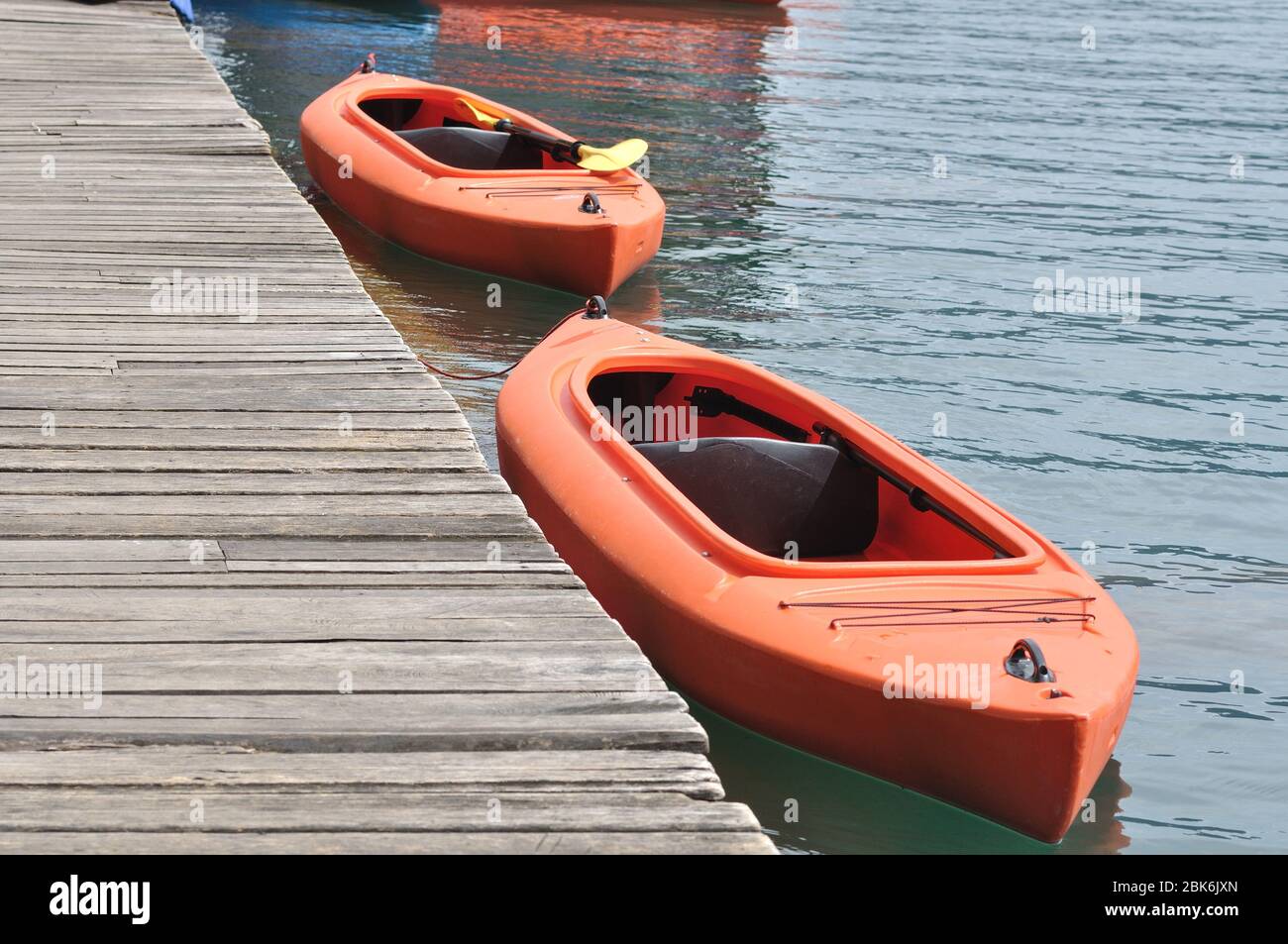 Two orange kayak beside wooden dock Stock Photo - Alamy