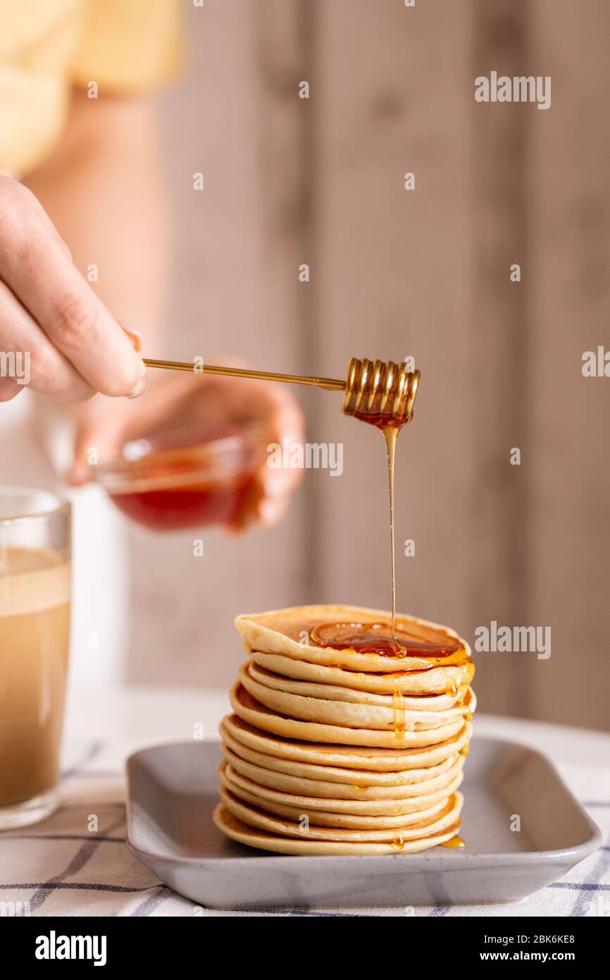 Hand of young housewife standing by table and putting fresh honey on ...