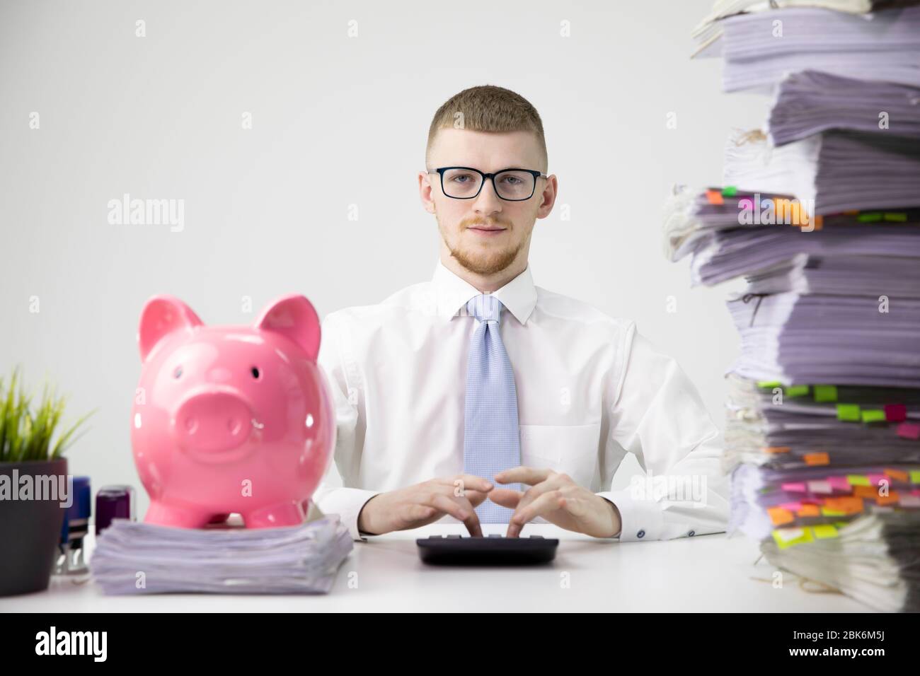Smart office worker calculates bills, lot of paperwork, large piggy ...