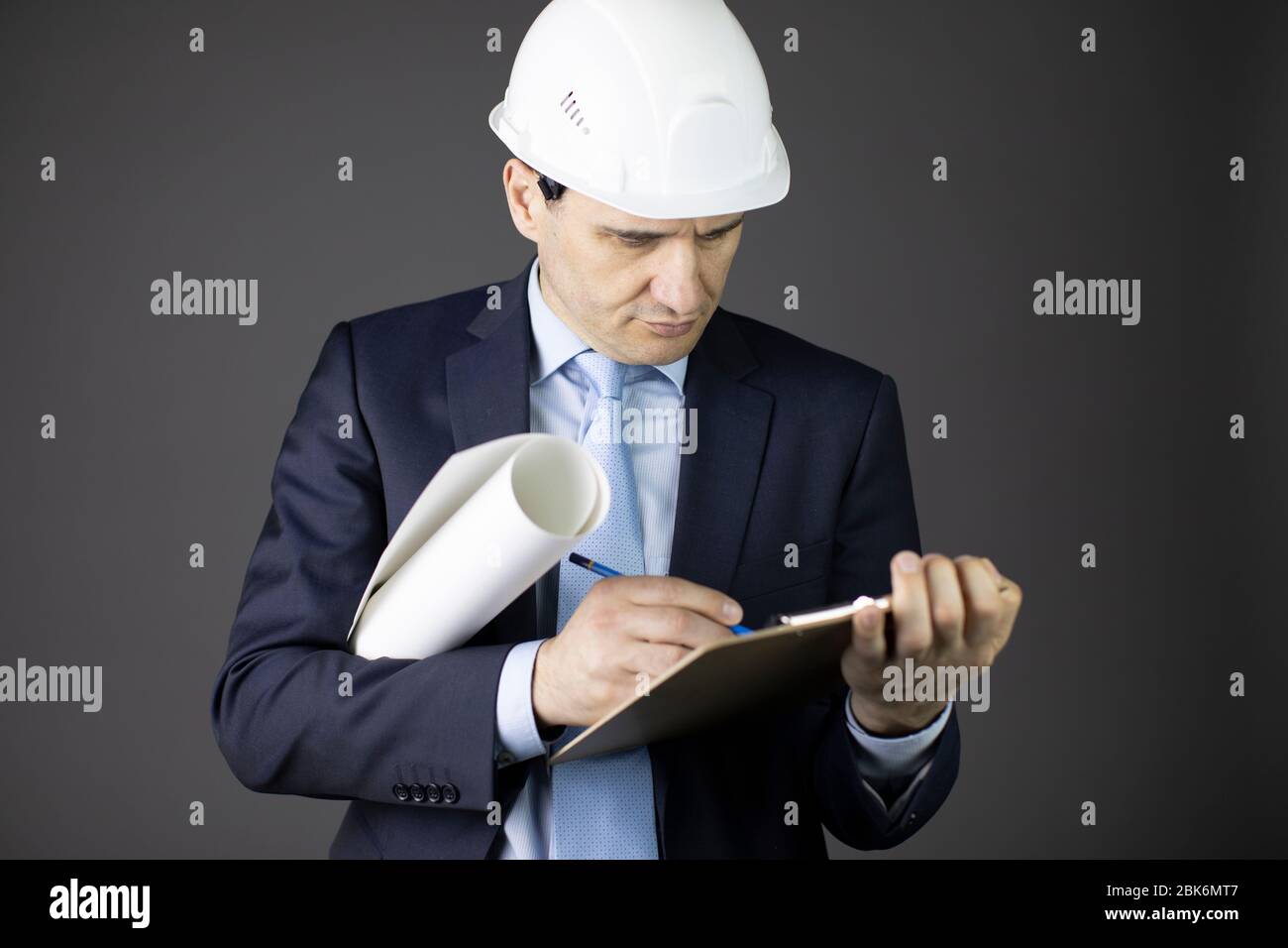 Chief engineer in safety helmet makes notes on clipboard holds ...