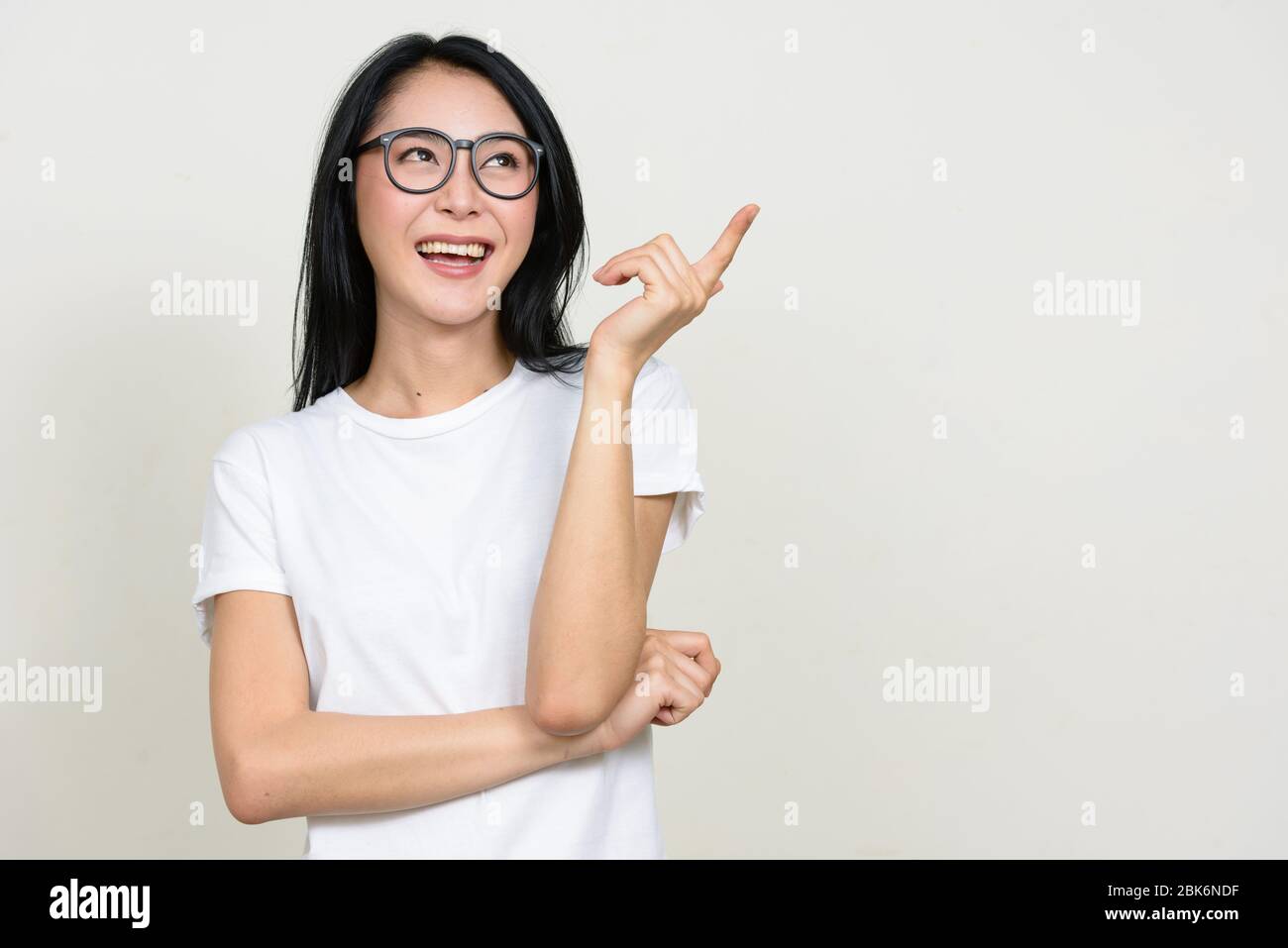 Happy young beautiful Asian nerd woman pointing up and having idea Stock Photo - Alamy