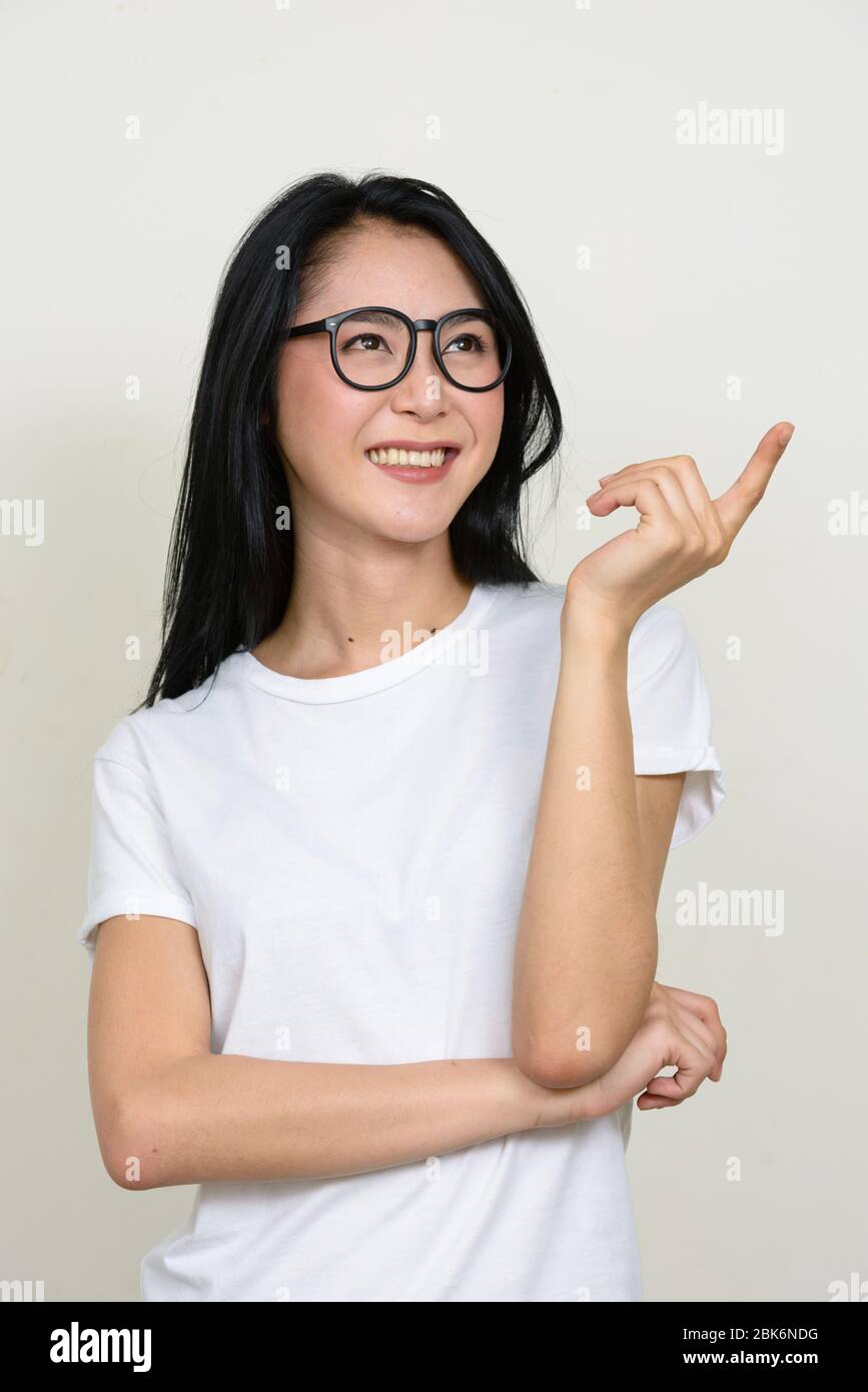 Happy young Asian nerd woman pointing up and having idea Stock Photo ...