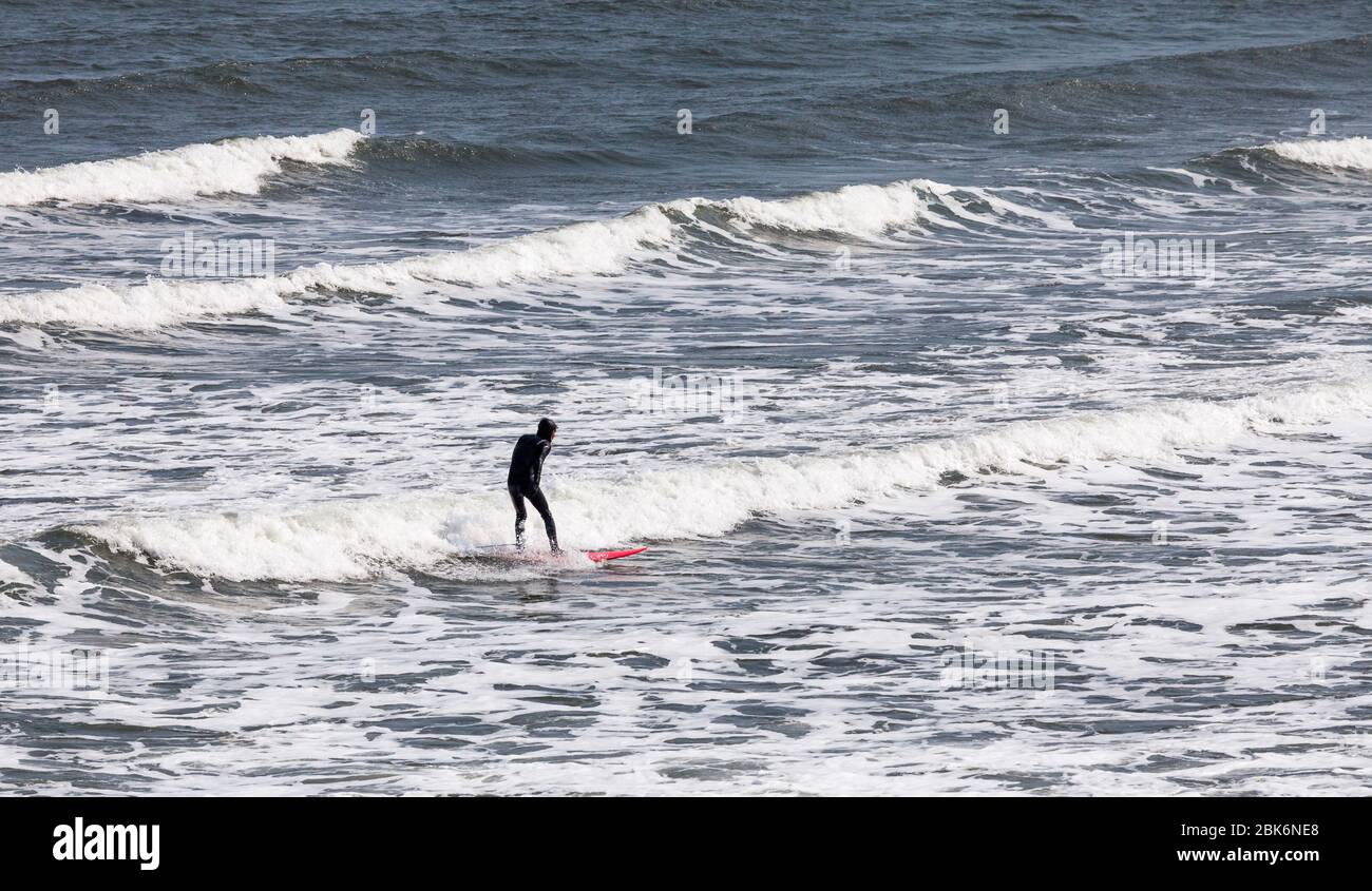 A man surfing off the coast at Saltburn by the Sea in north east ...