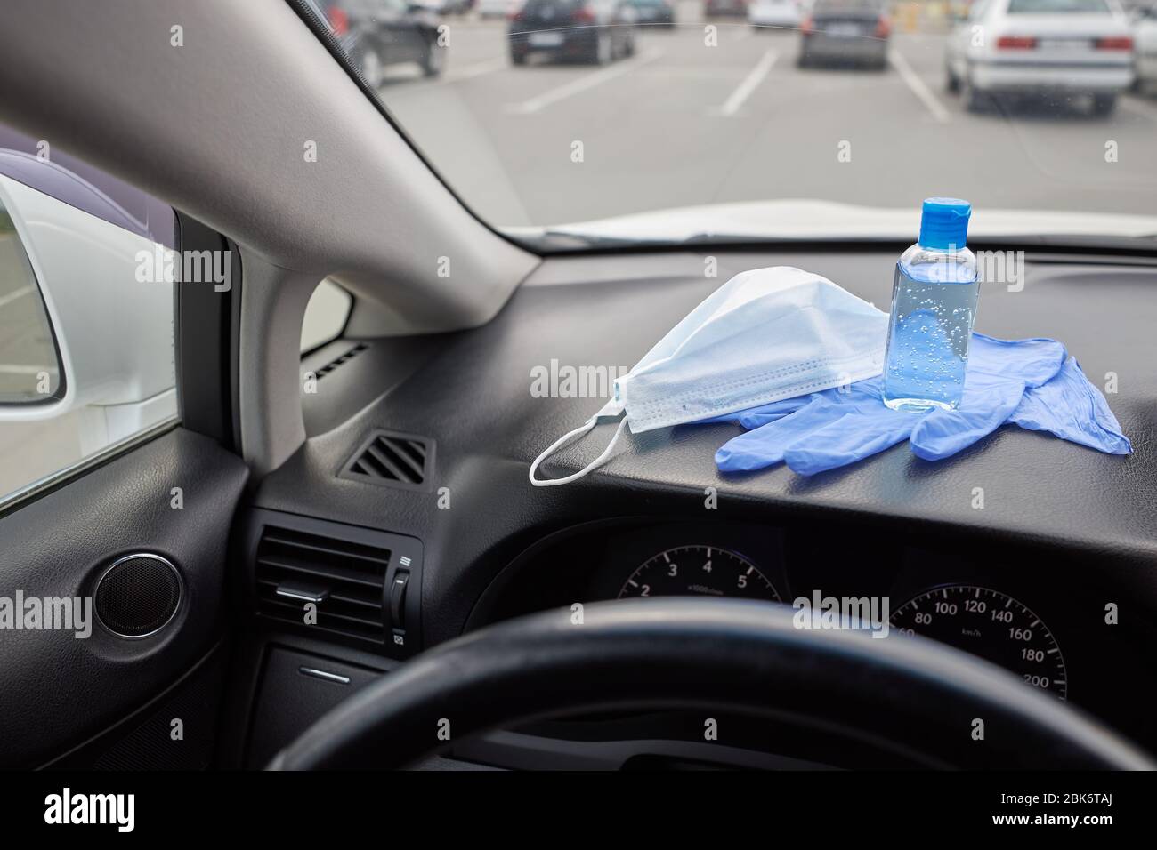 Medical mask, gloves and an antiseptic vial lie on the cars dashboard ...