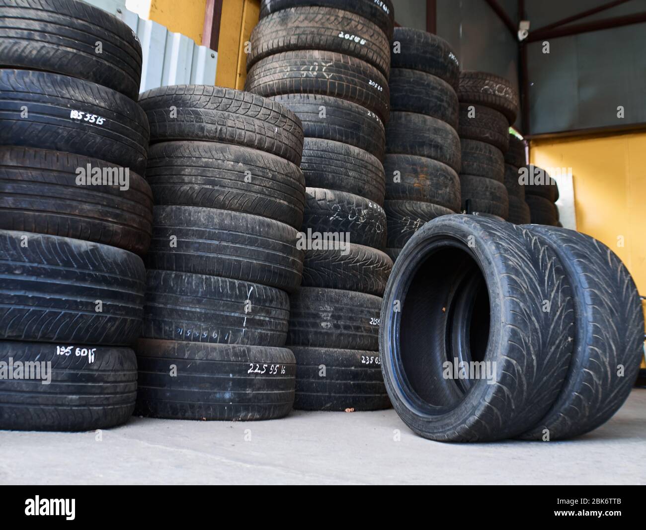 Used car tires stacked in piles at junkyard. Old wheels recycling and utilization concept. Tire ...