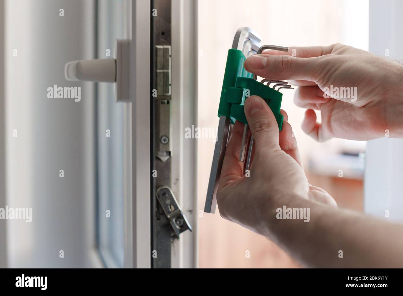 Man's hand choose allen key for adjustment of hardware of the uPVC door ...