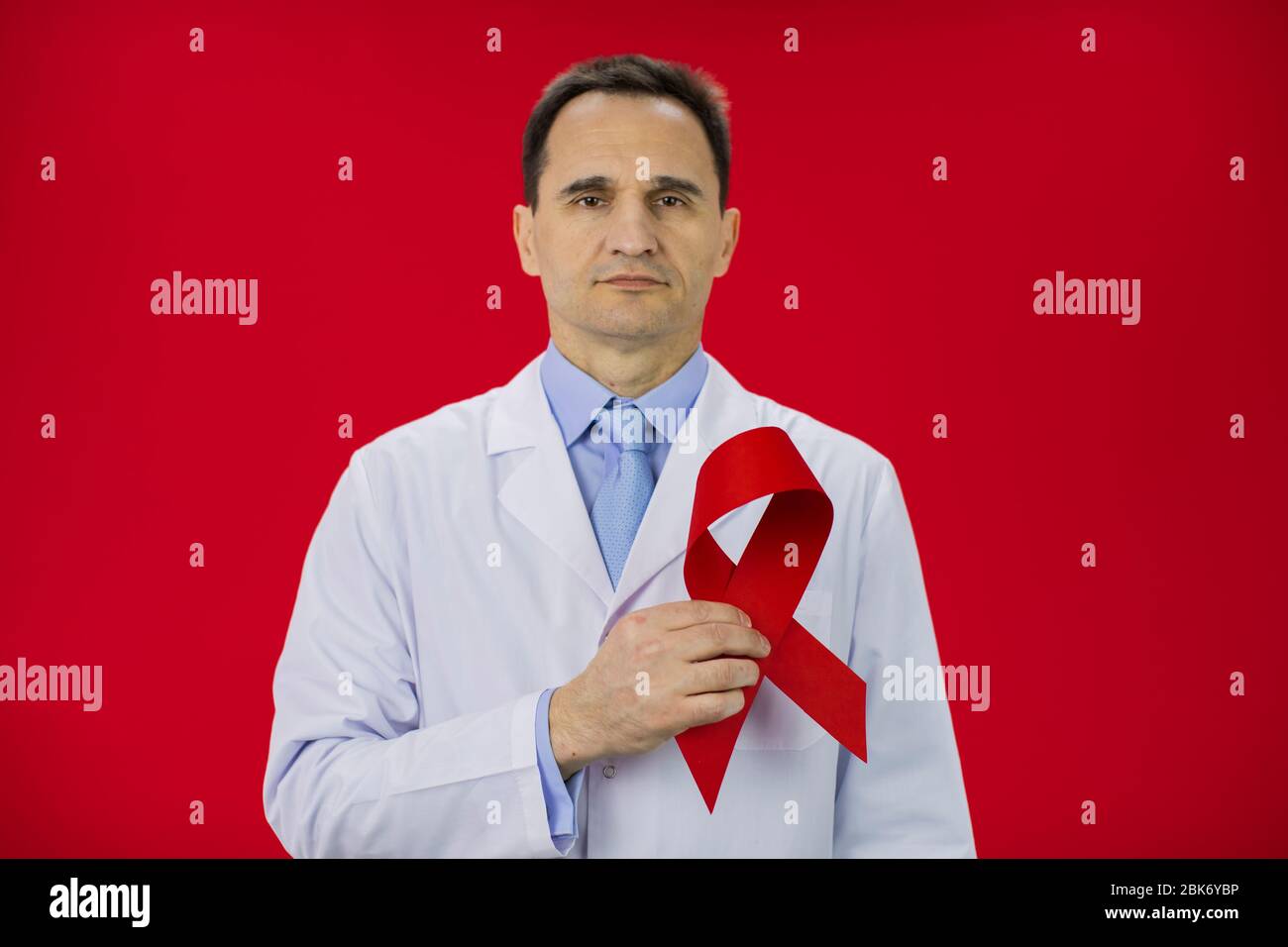 40s medical doctor with big red ribbon for AIDS HIV awareness on red ...