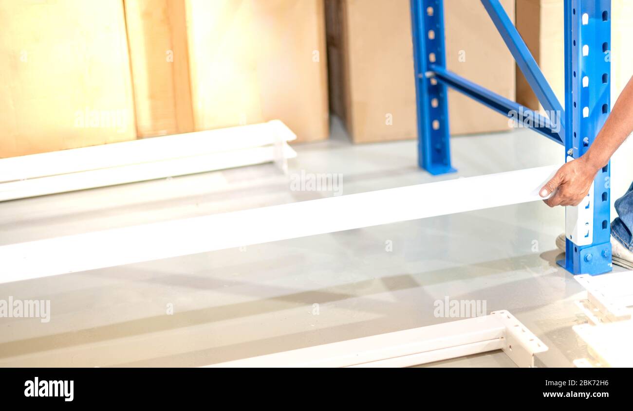 Male hand preparing to assembling the metal rack in in warehouse or ...