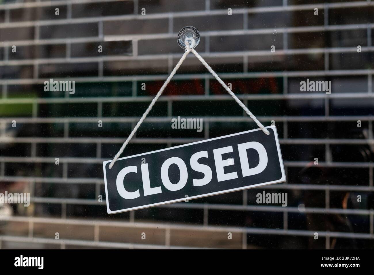 A closed sign on a shop window with security mesh in the background ...