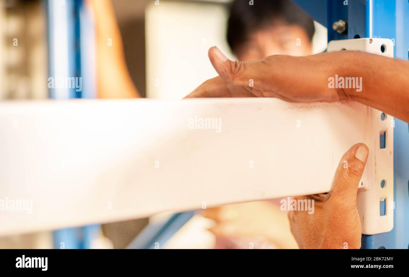 Male hand preparing to assembling the metal rack in in warehouse or ...