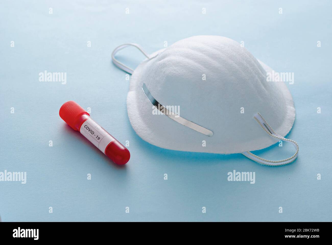 Face mask with blood sample in a test tube labelled Covid-19 in a ...