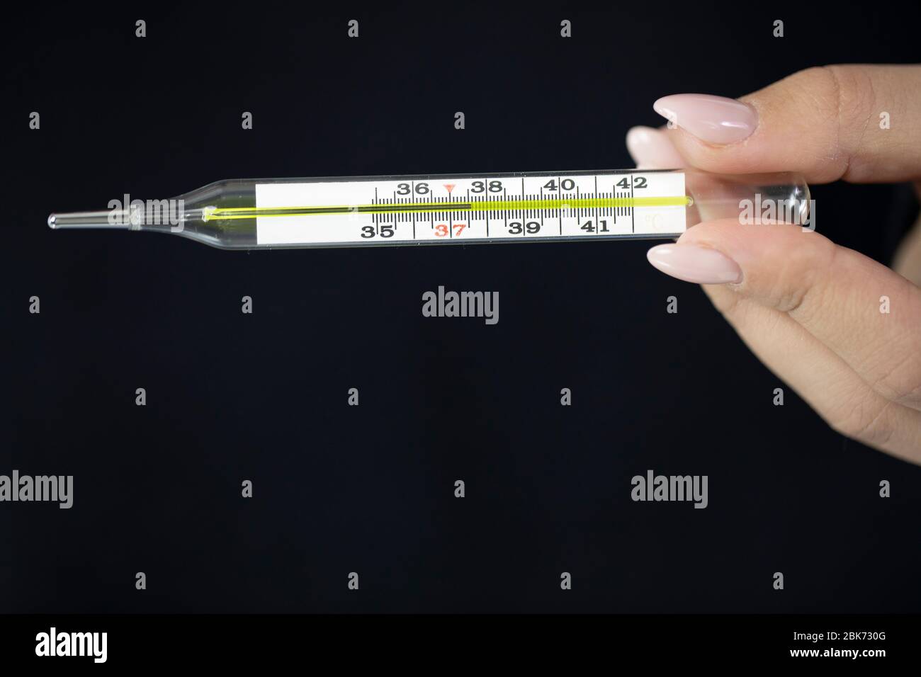 Female holds mercury medical thermometer in hand which shows above 37 ...