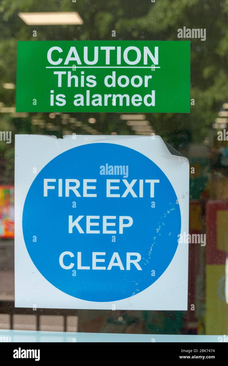 a close up view of a caution and fire exit warning sign on a shop ...