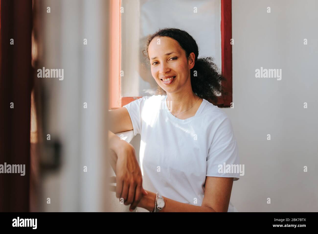 pretty black woman smiling at window Stock Photo - Alamy
